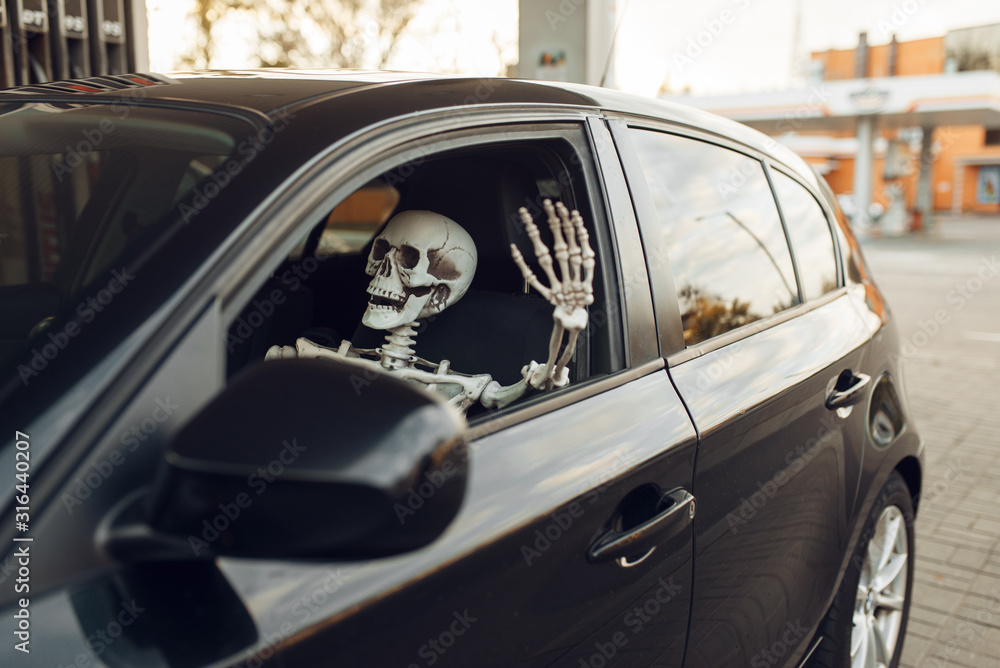 Foto de Skeleton in car, fueling on gas station do Stock | Adobe Stock
