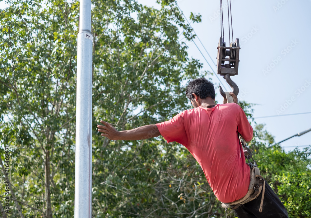 Worker without any safety and protective equipment is hanging on crane ...