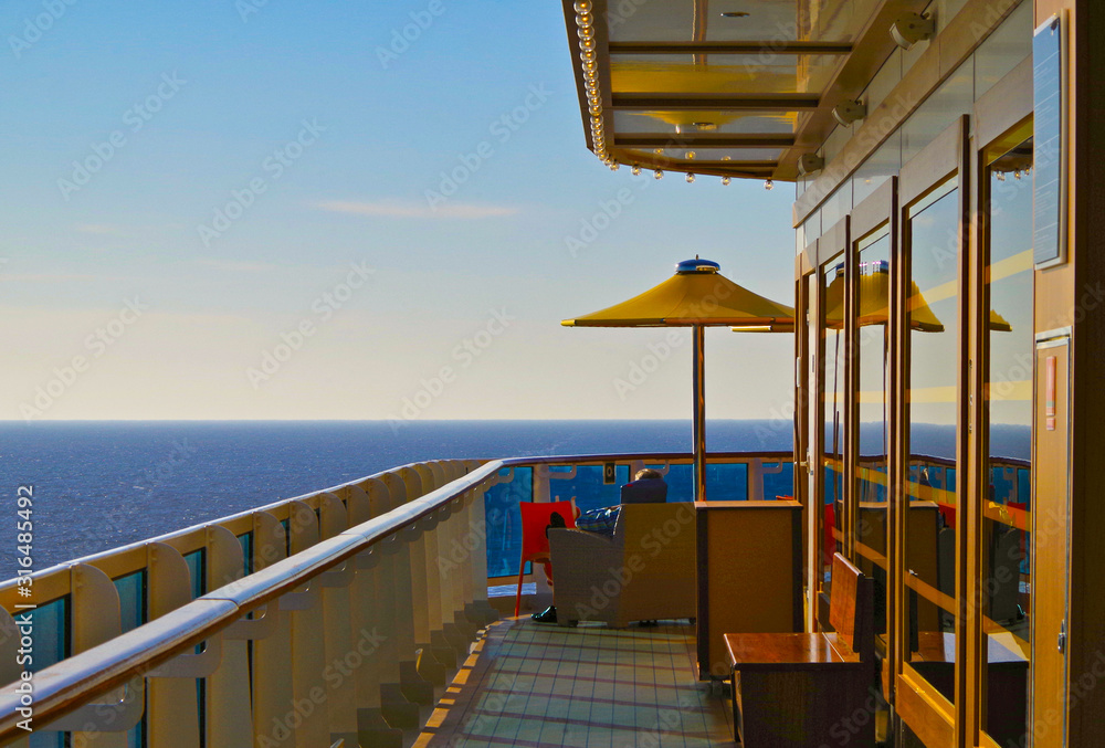 Relaxing on outdoor promenade with sun umbrellas and deck chairs with ...