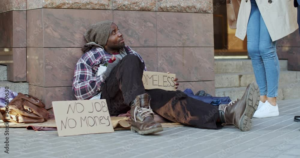 African American young homeless man sitting on the street and asking ...