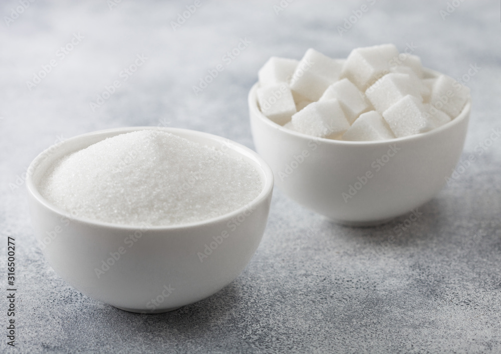 White bowl plates of natural white sugar cubes and refined sugar on ...