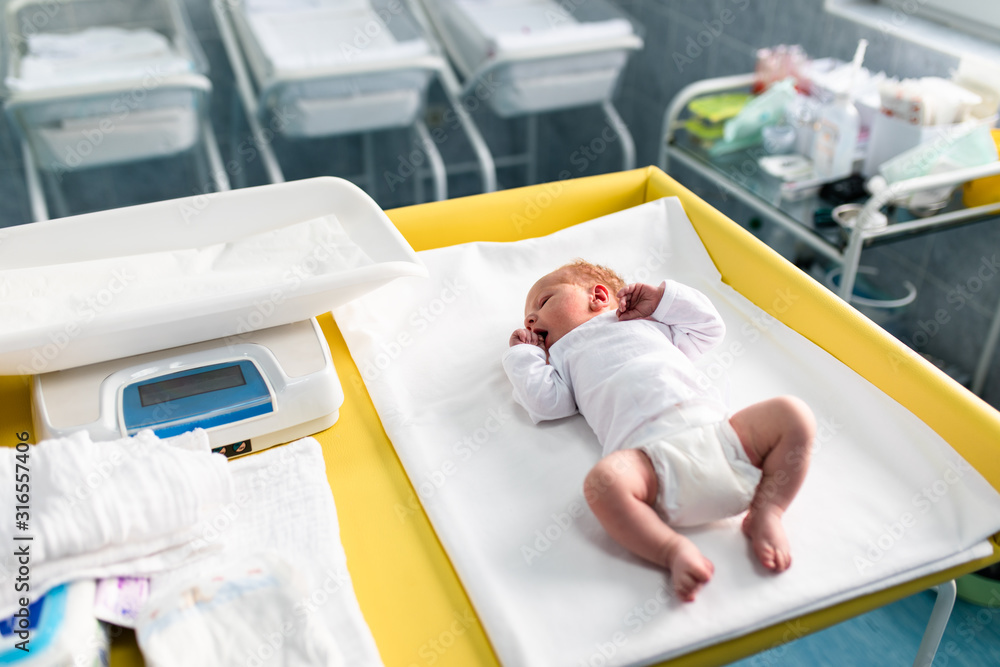 Newborn baby laying and slipping in maternity ward bed. After birth ...