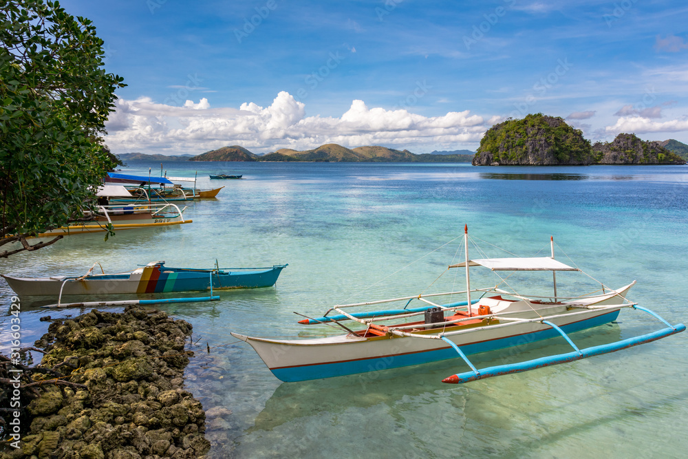Traditional wooden Filipino boats by the beach of a small island in the ...