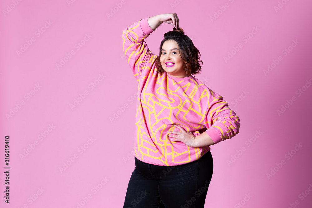 Happy plus size model in casual clothes, fat woman on pink background ...