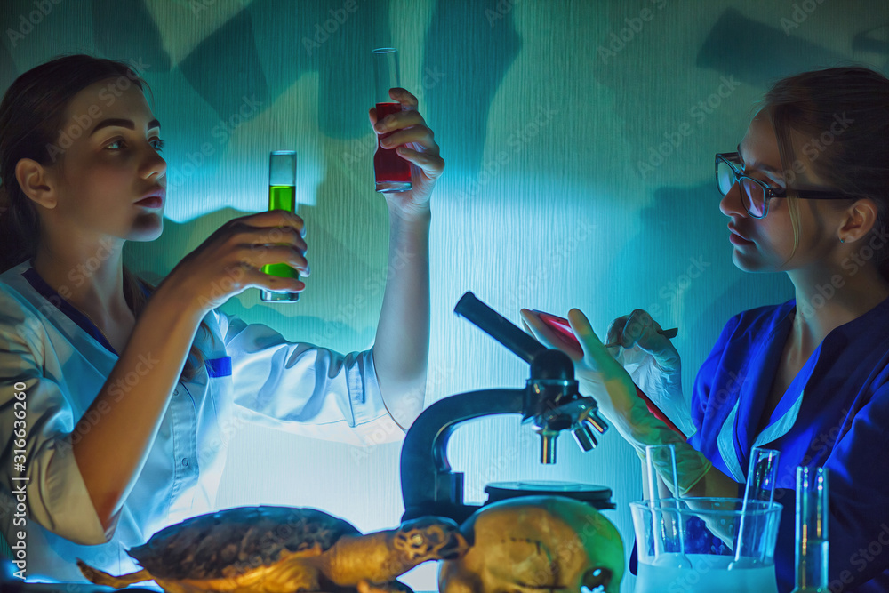 Student girl looking in a microscope, science laboratory concept. Two ...