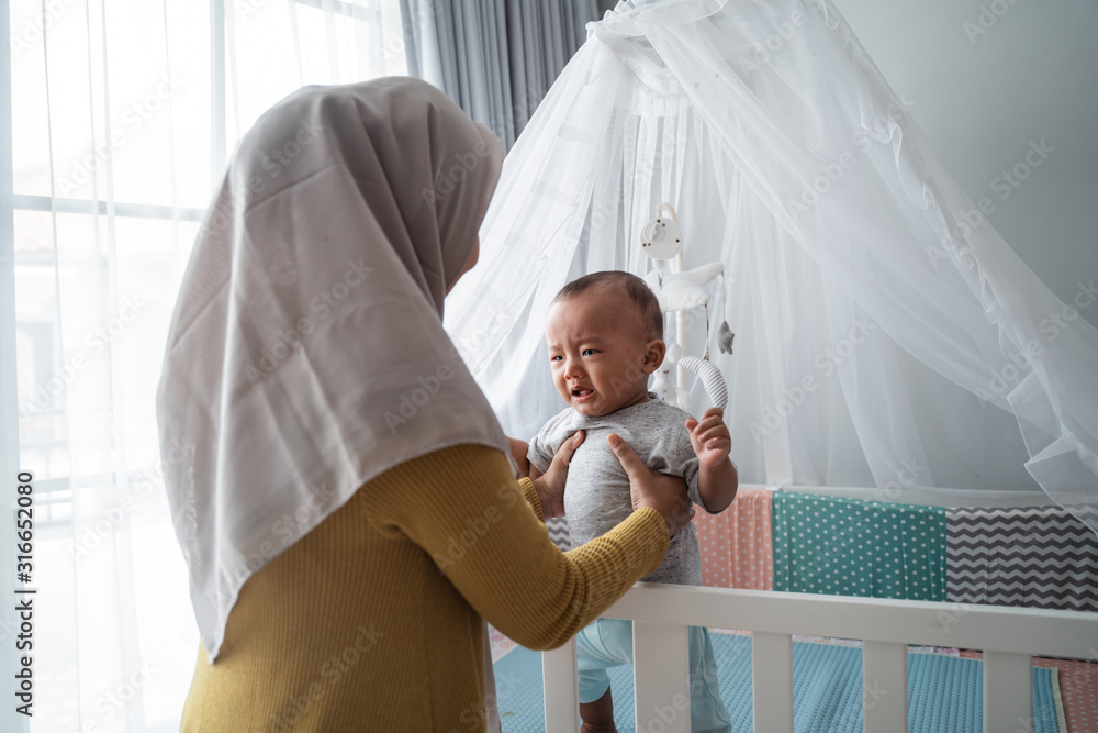muslim mother looking at her baby boy crying at the crib Stock Photo ...