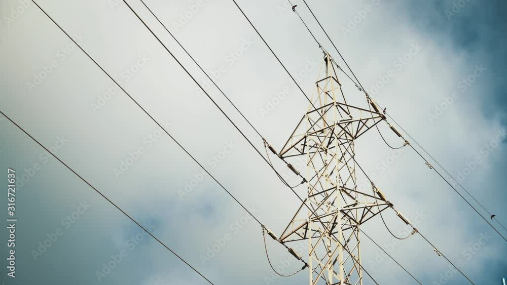 Gimbal shot of high concrete electric pole against the blue sky with ...