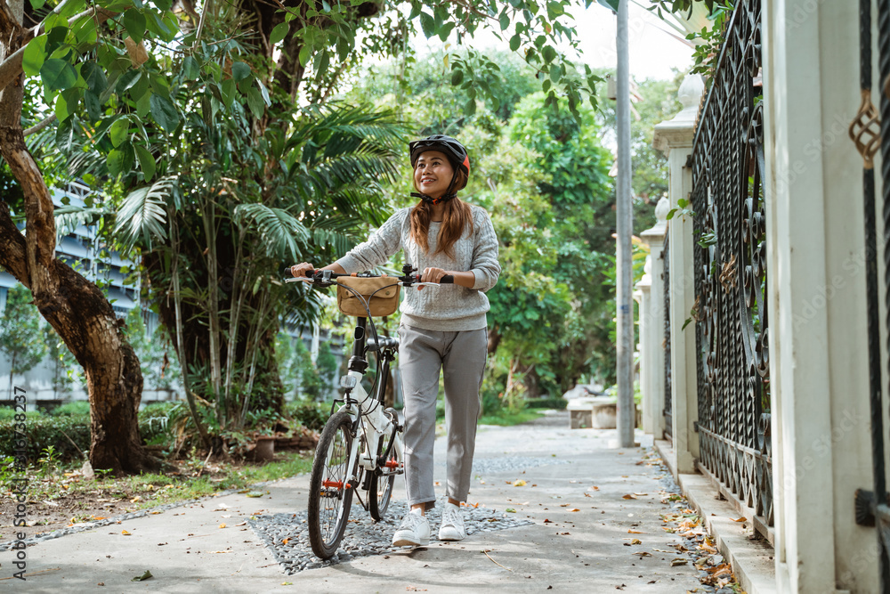 beautiful young women walk on folding bikes on the road wearing helmets ...