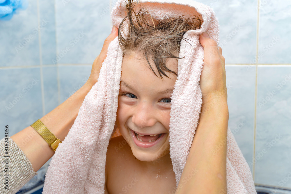 Mom wipes the baby with a towel after bathing in the shower, a joyful ...
