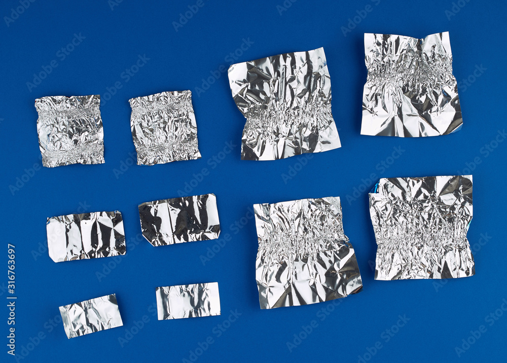 various crumpled foil used candy wrappers on a blue background Stock ...