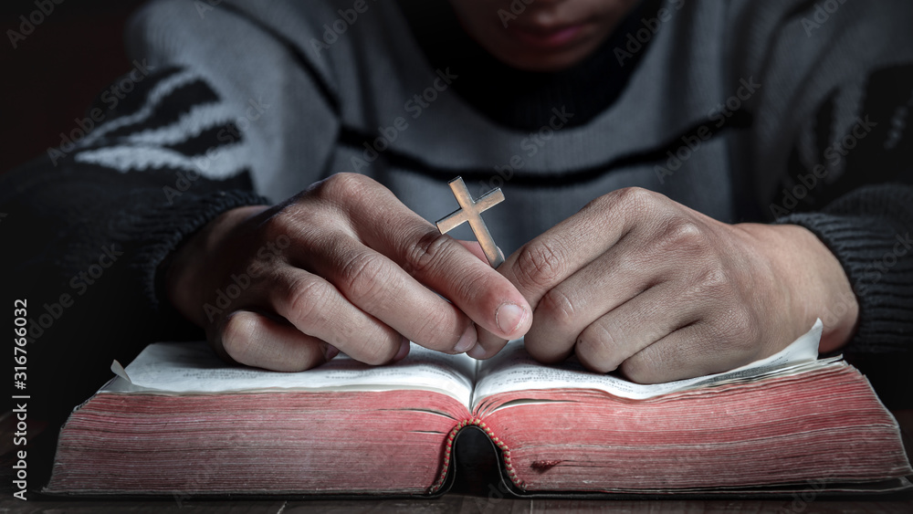 Praying hands of male with the silver Cross on holy bible. christian ...