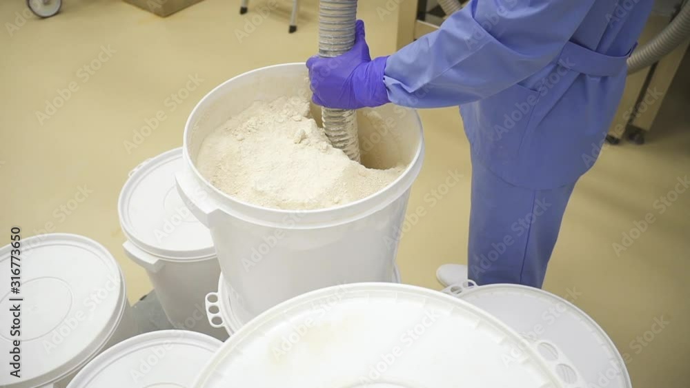worker blowing drug material powder in the containers at pharmaceutical ...