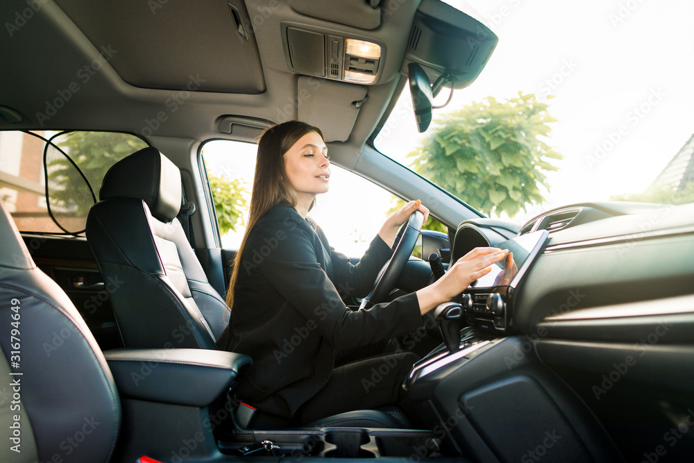Businesswoman in black suit sits behind the wheel of a premium car and ...