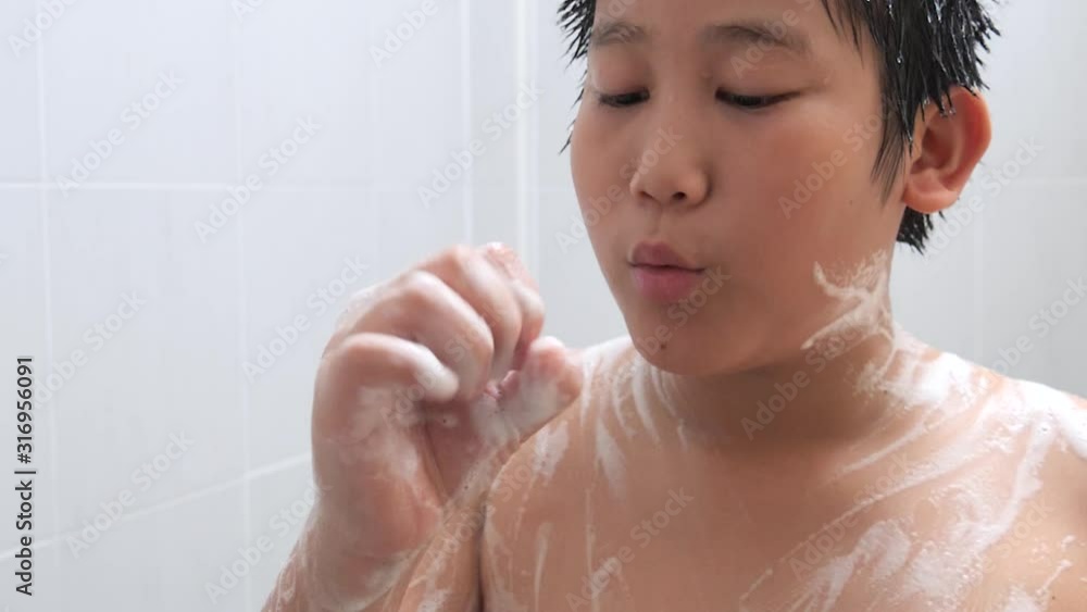 The child takes a shower. Happy boy in the bathroom playing with bubble ...