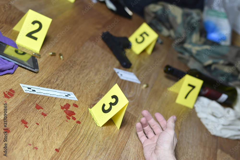 Hand of dead victim surrounded by evidence markers and objects on floor ...