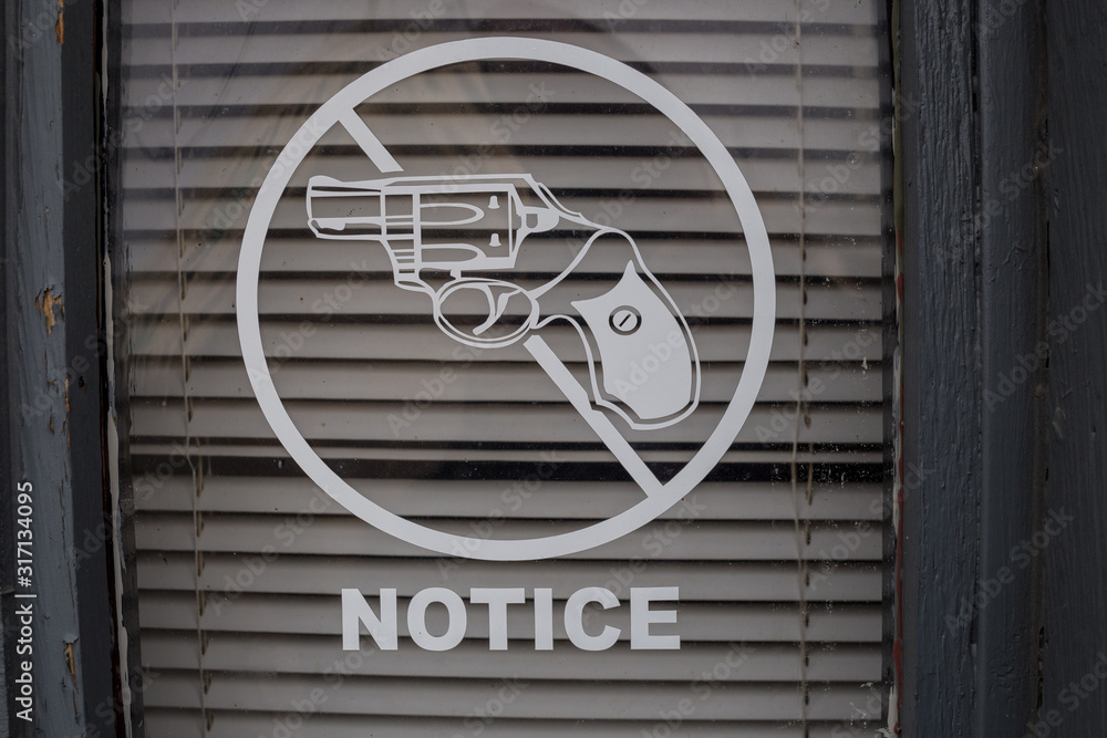 No guns allowed notice sticker on window with blinds Stock Photo ...