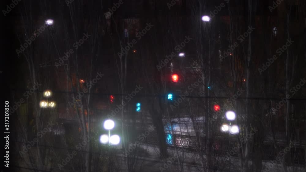 Bright lights of traffic lighter. Cars with headlights on, passing by ...