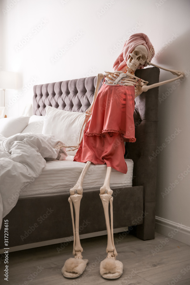 Human skeleton in silk pajamas and towel sitting on bed indoors Stock ...