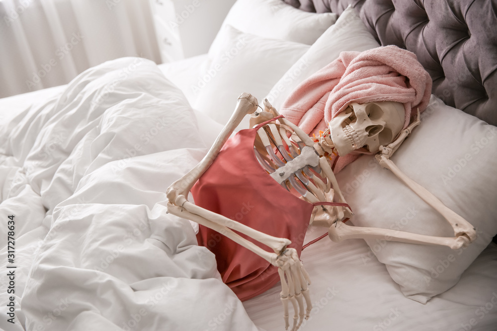 Human skeleton in silk pajamas and towel lying on bed indoors Stock ...