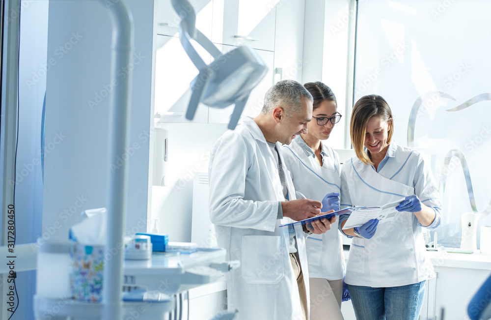A group of skilled dentists comes together in a dental office ...