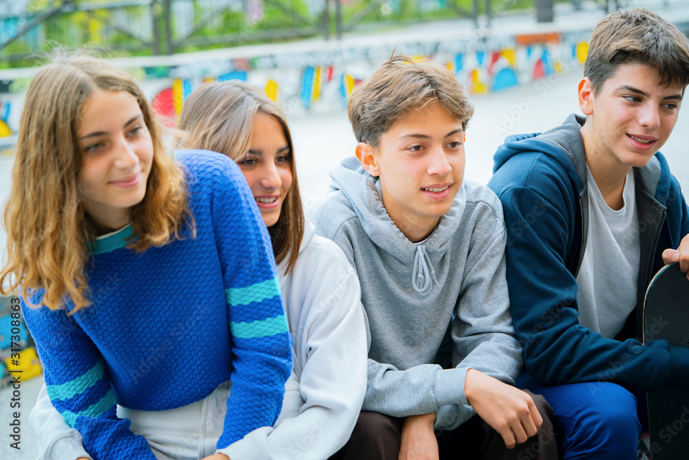 Smiling teenage friends sitting outdoors Stock Photo | Adobe Stock