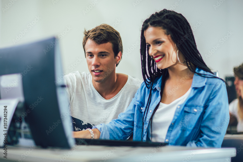 College students sitting in a classroom, using computers during class ...