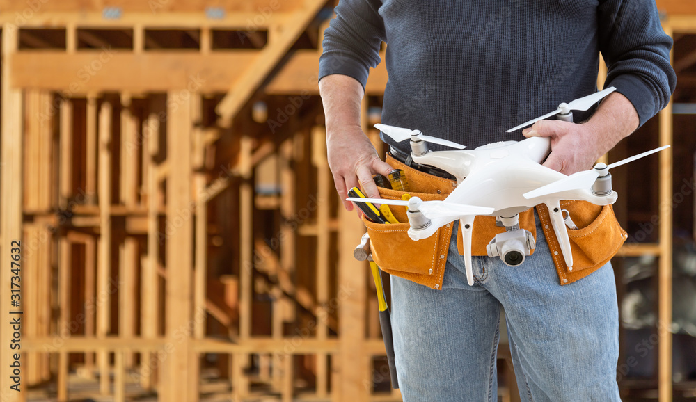 Construction Worker and Drone Pilot With Toolbelt Holding Drone At ...
