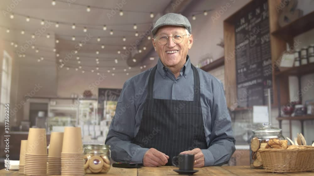 Happy handsome mature white haired cafe owner in a coffee house giving ...