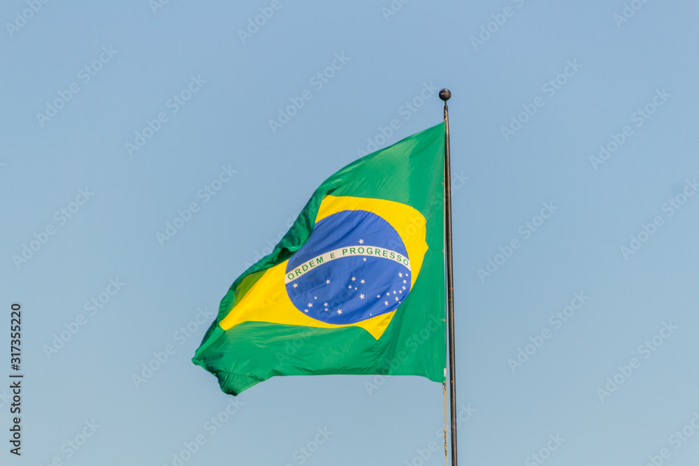 Fotografia do Stock: Brazilian flag flying with blue sky background ...