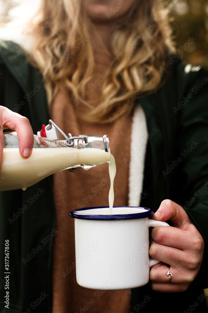 Crop female in warm casual clothes filling white metal cup with tasty ...