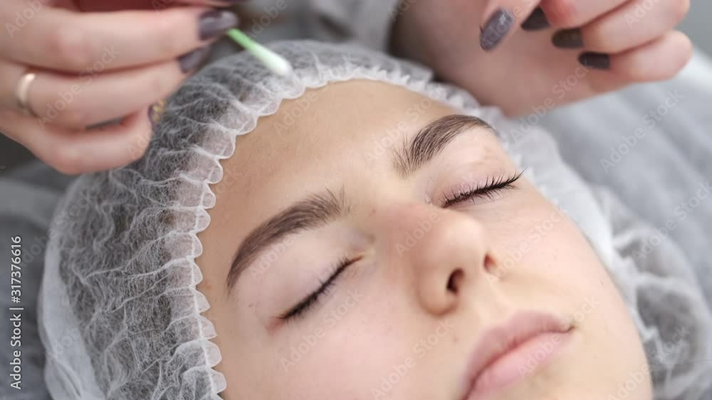 A lash maker is finishing the procedure of eye lash lamination. The professional have laminated ...