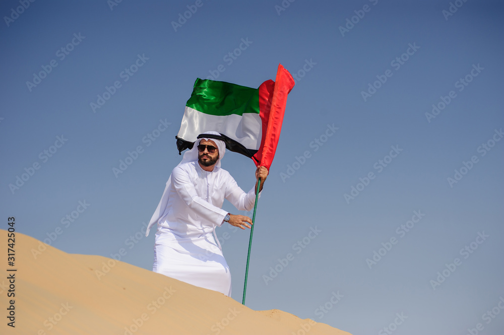 Proud arabian Emirati man holding a UAE flag in the desert. Stock Photo ...
