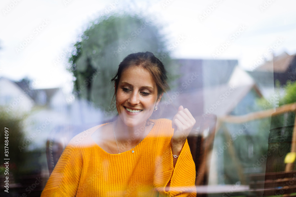 Young woman sitting laughing behind a window Stock Photo | Adobe Stock