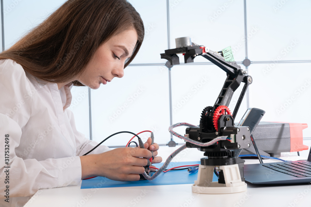 A young woman writes an algorithm for the robot arm. Science Research ...