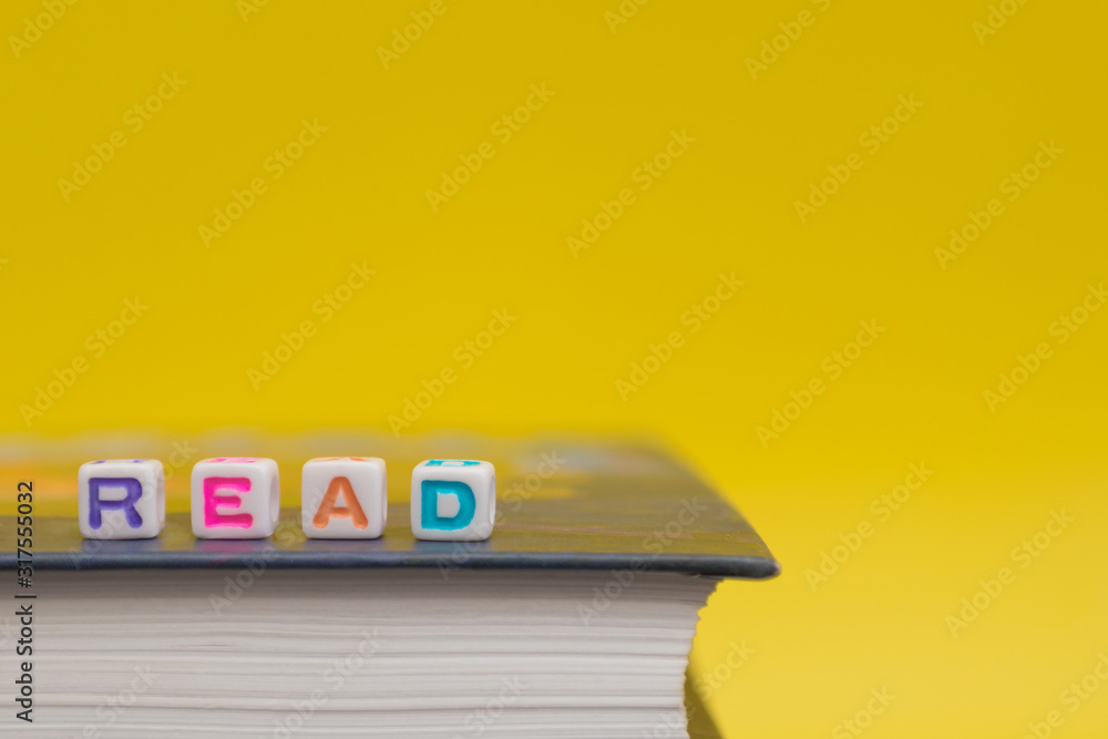Word 'Read' written with cube colored letters on book surfase on yellow ...
