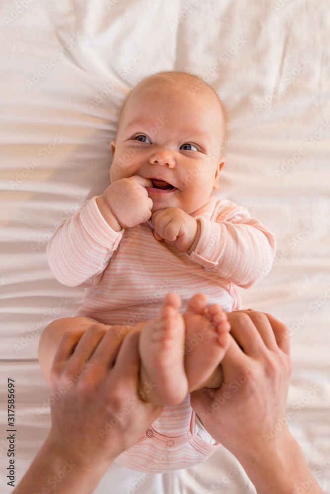 Newborn baby lying on the bed, Dad holding the baby's legs with his ...