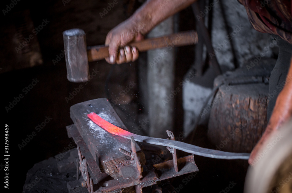 Blacksmith's hands at work. In one hand a hammer, in the other a ...