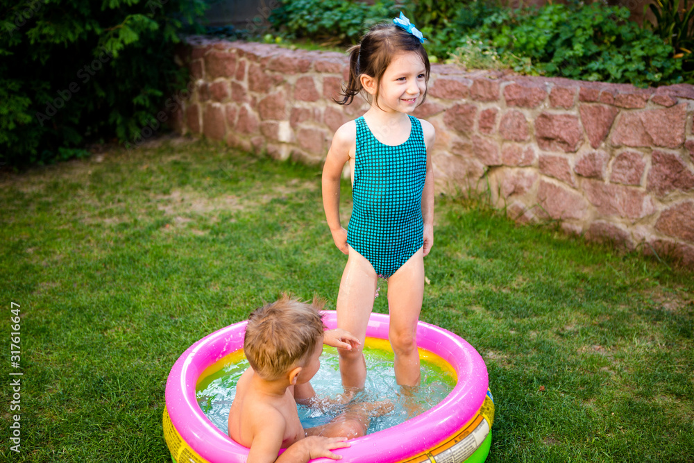 Two little brother and sister playing and splashing in pool on hot ...