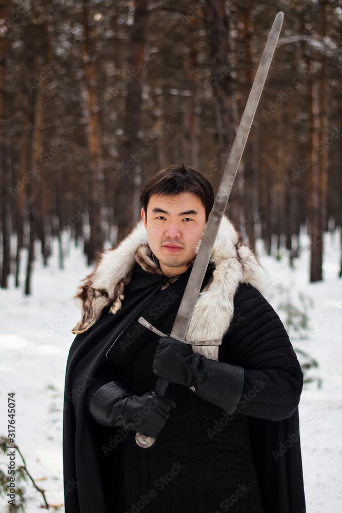 A warrior in black quilted clothes in a black cloak with a white fur ...