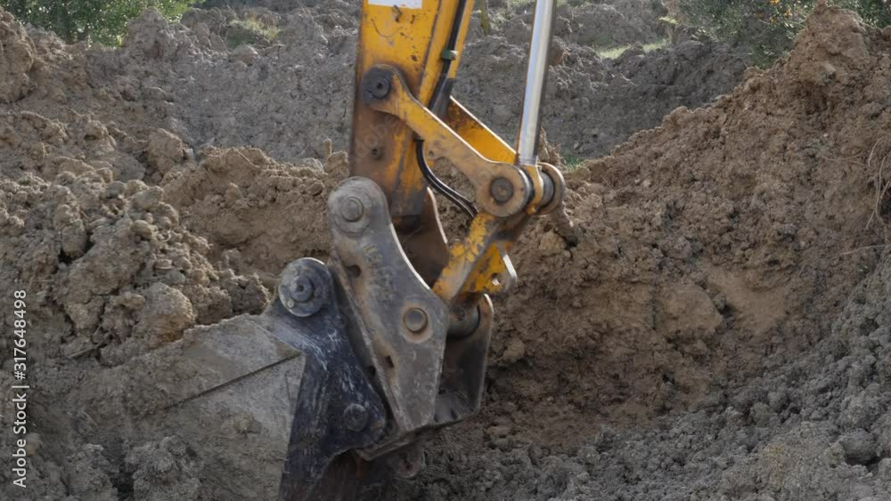 Close-up of an excavator scoop as it removes dirt and mud from a ...