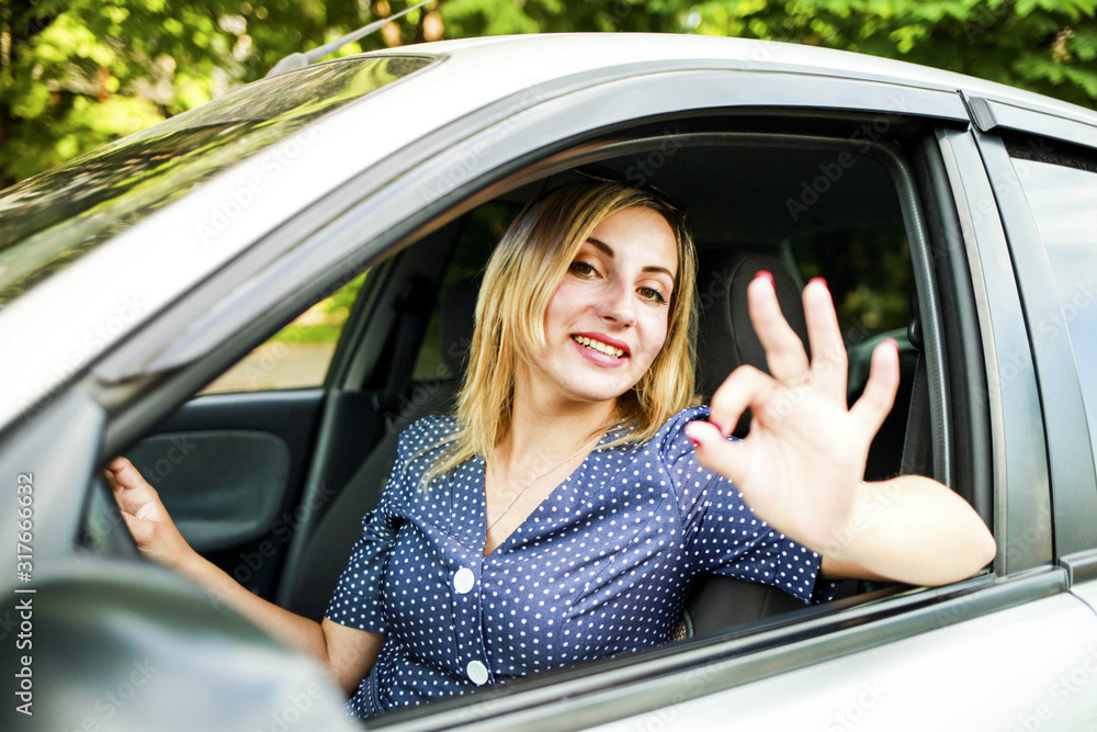 nice young blonde girl driving a car shows a hand gesture everything is ...