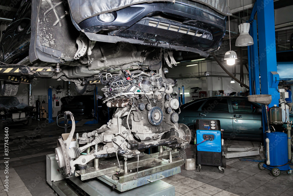 Replacement used engine on a table mounted under raised car on lift for ...