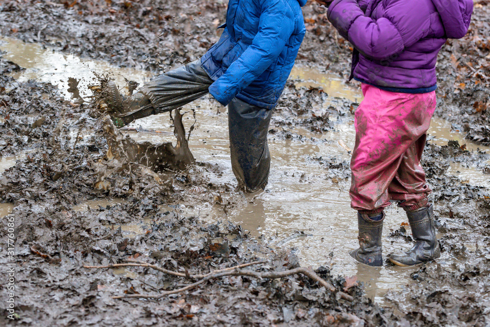 Young children playing in a muddy puddle Stock Photo | Adobe Stock