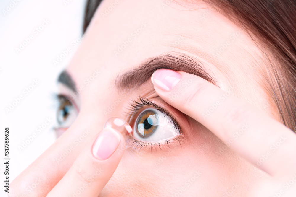 Closeup female face, finger is.holding soft contact lens. Woman is ...