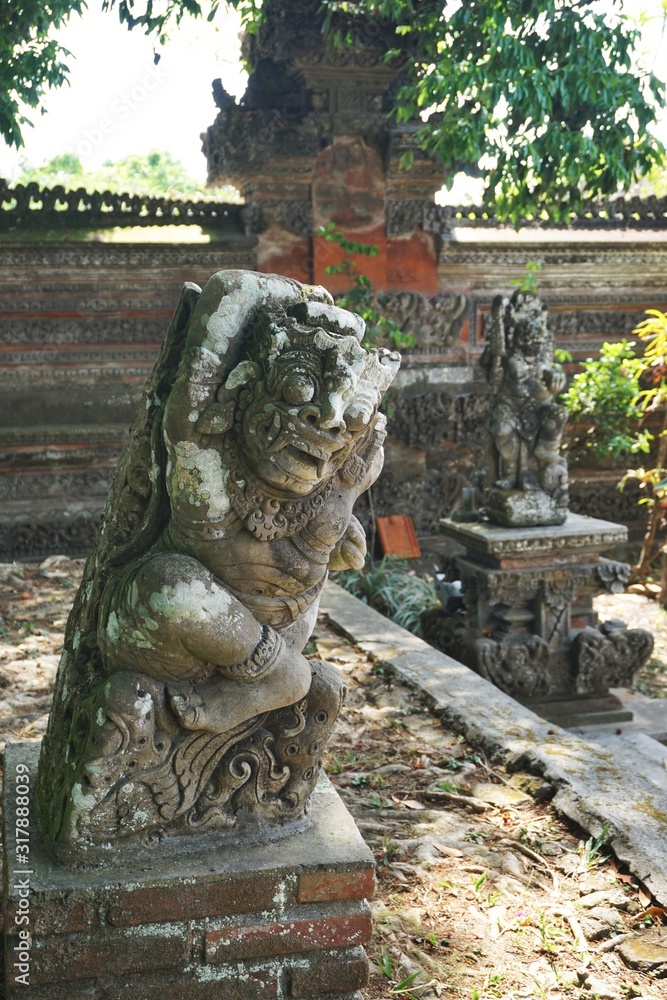 Ancient carved stone guardian statue in a shady spot outside a Hindu ...