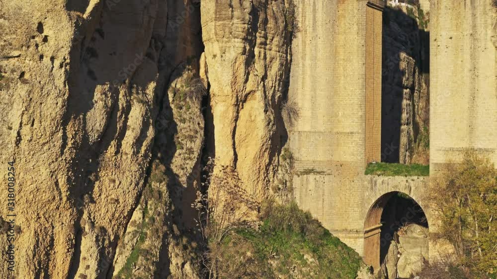 Tilt up shot of small waterfall under the stone bridge in Ronda city ...