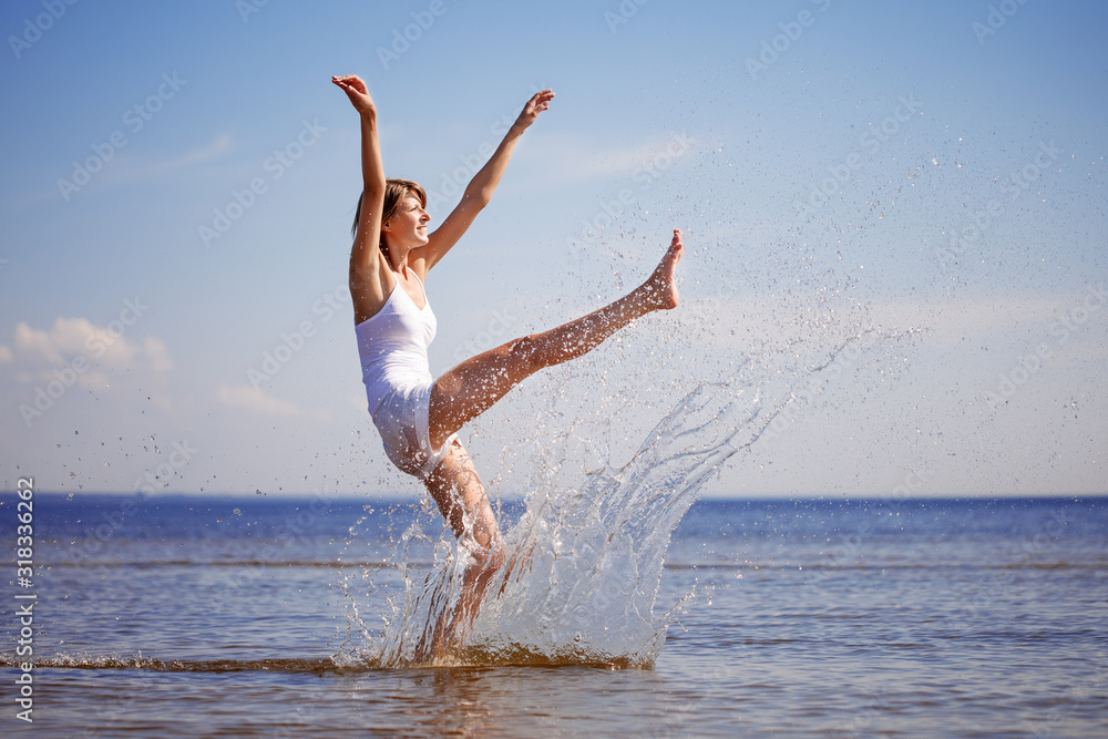 Woman enjoys on beach. Girl jumps on waves and laughs. Model in ...