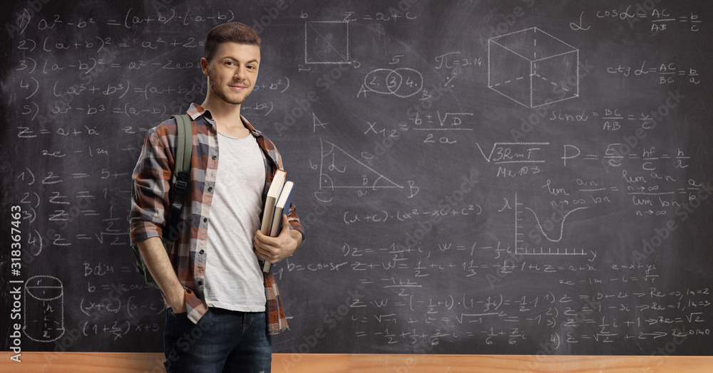 Male student posing in front of a blackboard with math formulas and ...