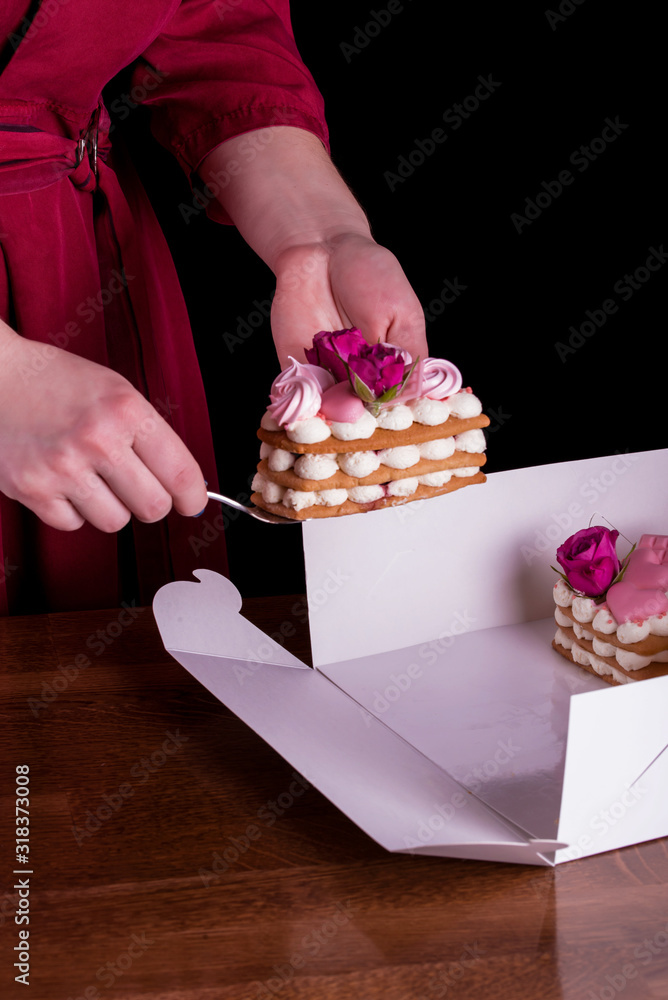 The hands of the confectioner with a delicate and delicious cake of ...