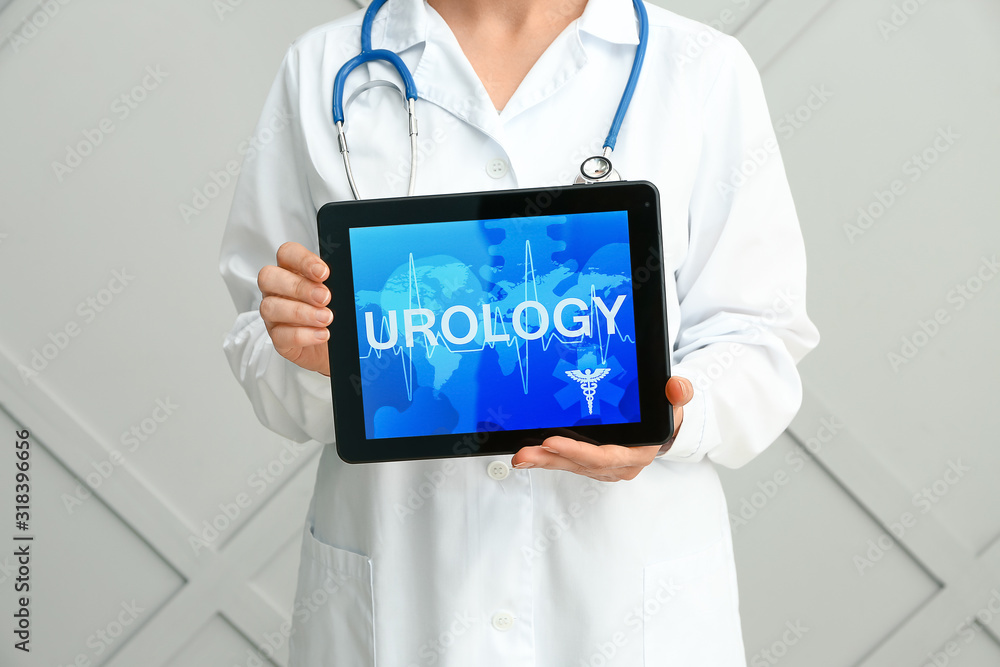 Doctor holding tablet computer with text UROLOGY on grey background ...